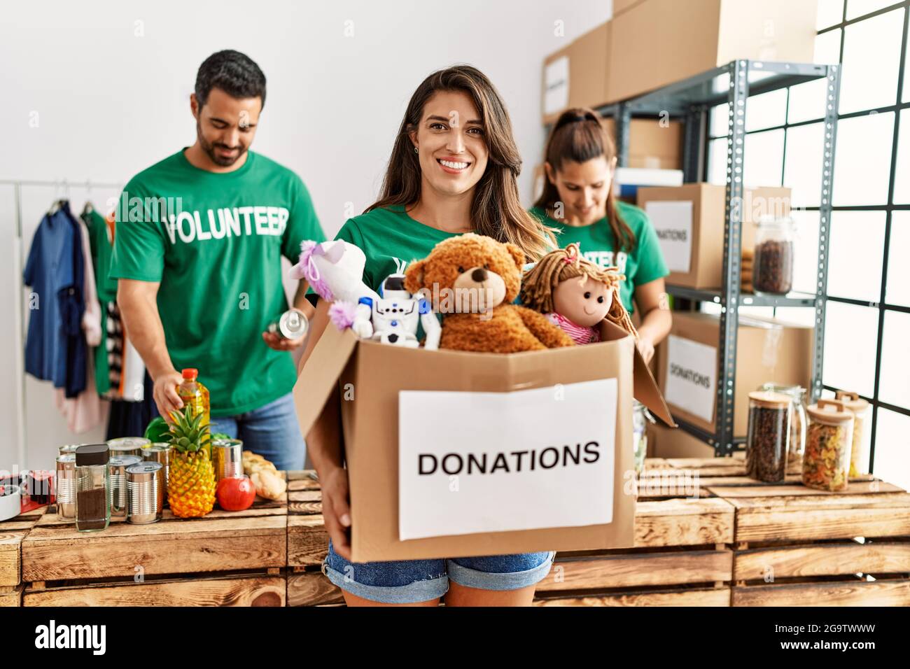 Group of hispanic volunteers working at charity center. Woman smiling ...
