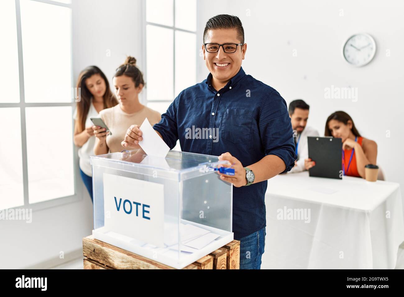 Young voter man smiling happy putting vote in voting box standing by ...