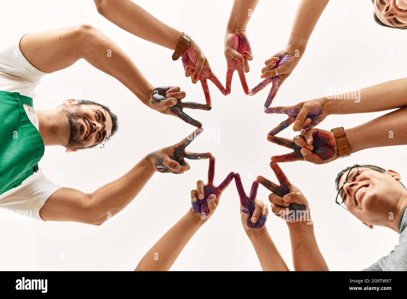 Group of people doing victory sign with fingers together at art studio ...