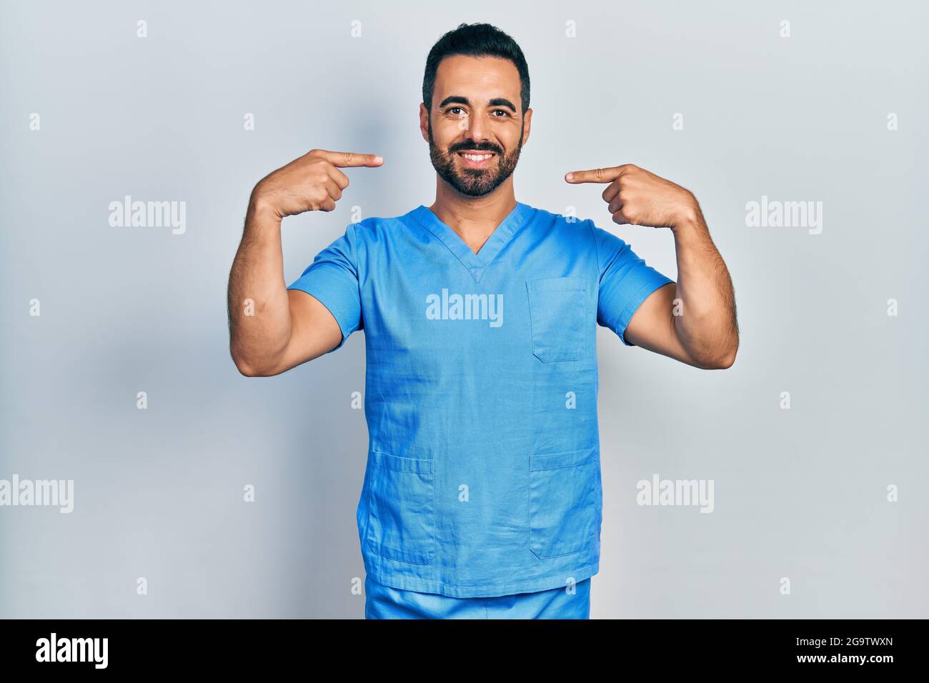 Handsome hispanic man with beard wearing blue male nurse uniform ...