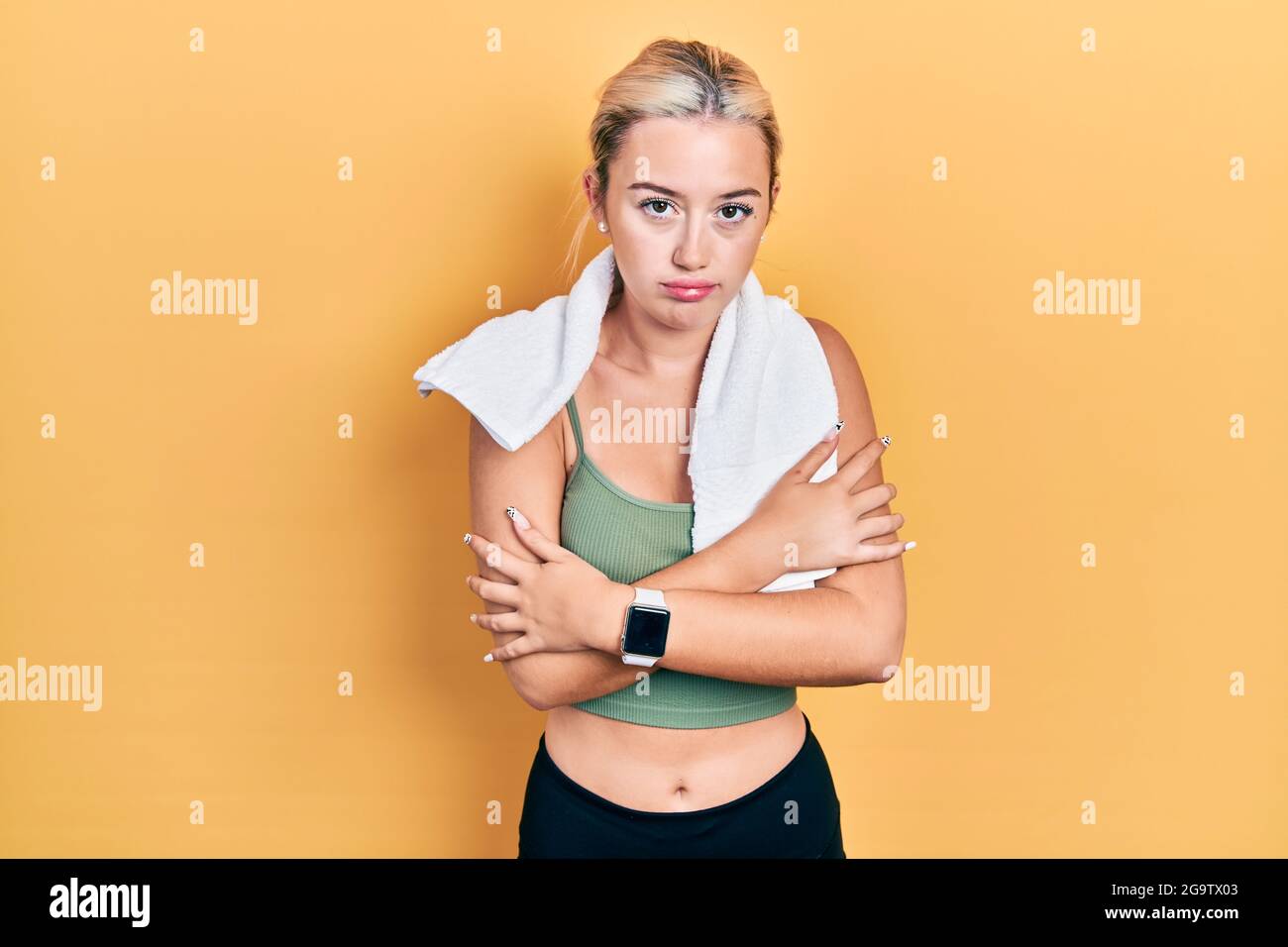 Young blonde girl wearing sportswear and towel shaking and freezing for ...