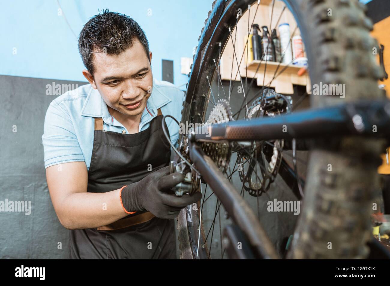 bicycle mechanic in apron checks the rear mech while fixing problems ...