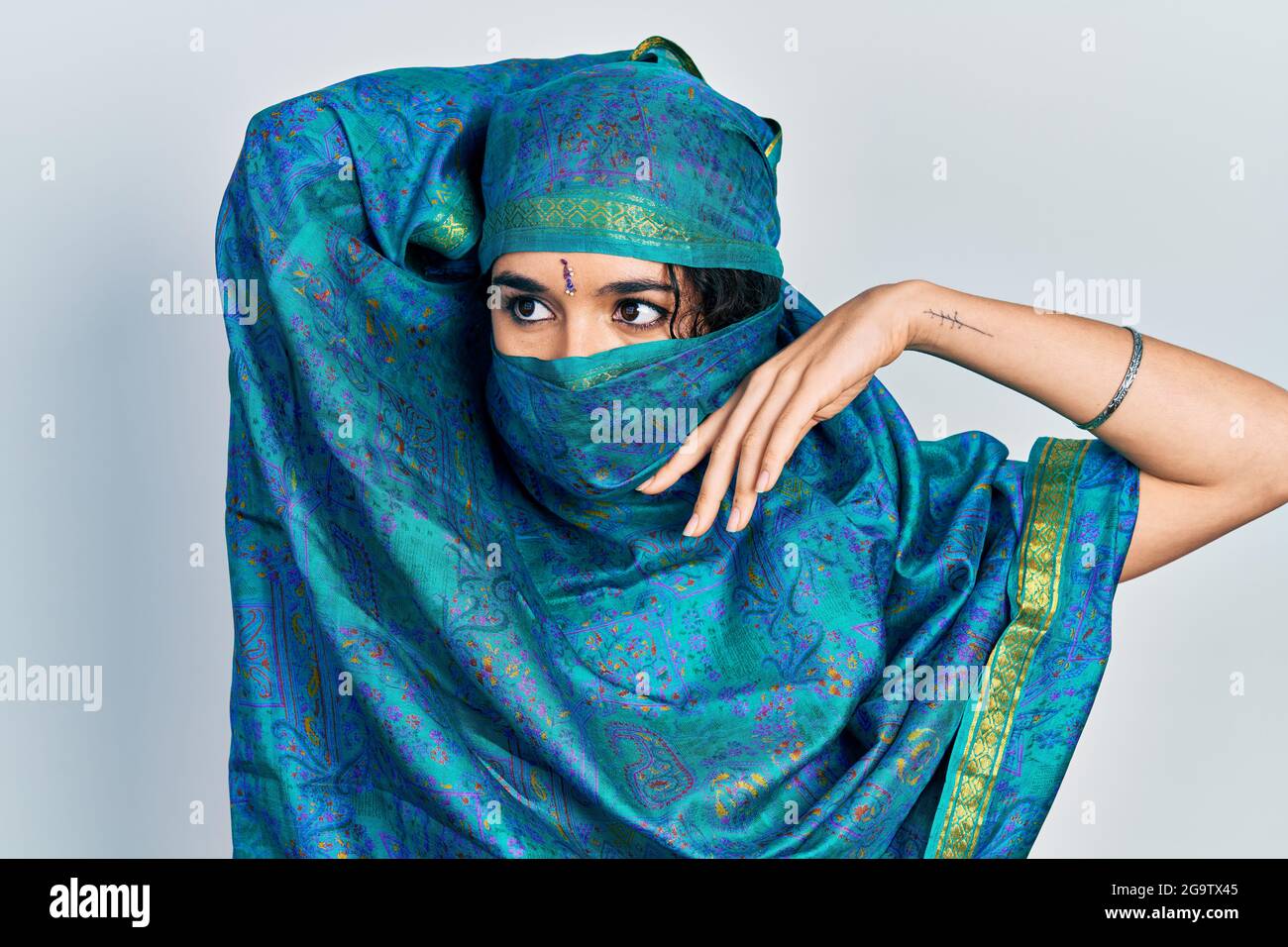 Young indian woman wearing sari covering head and face, doing elegant ...