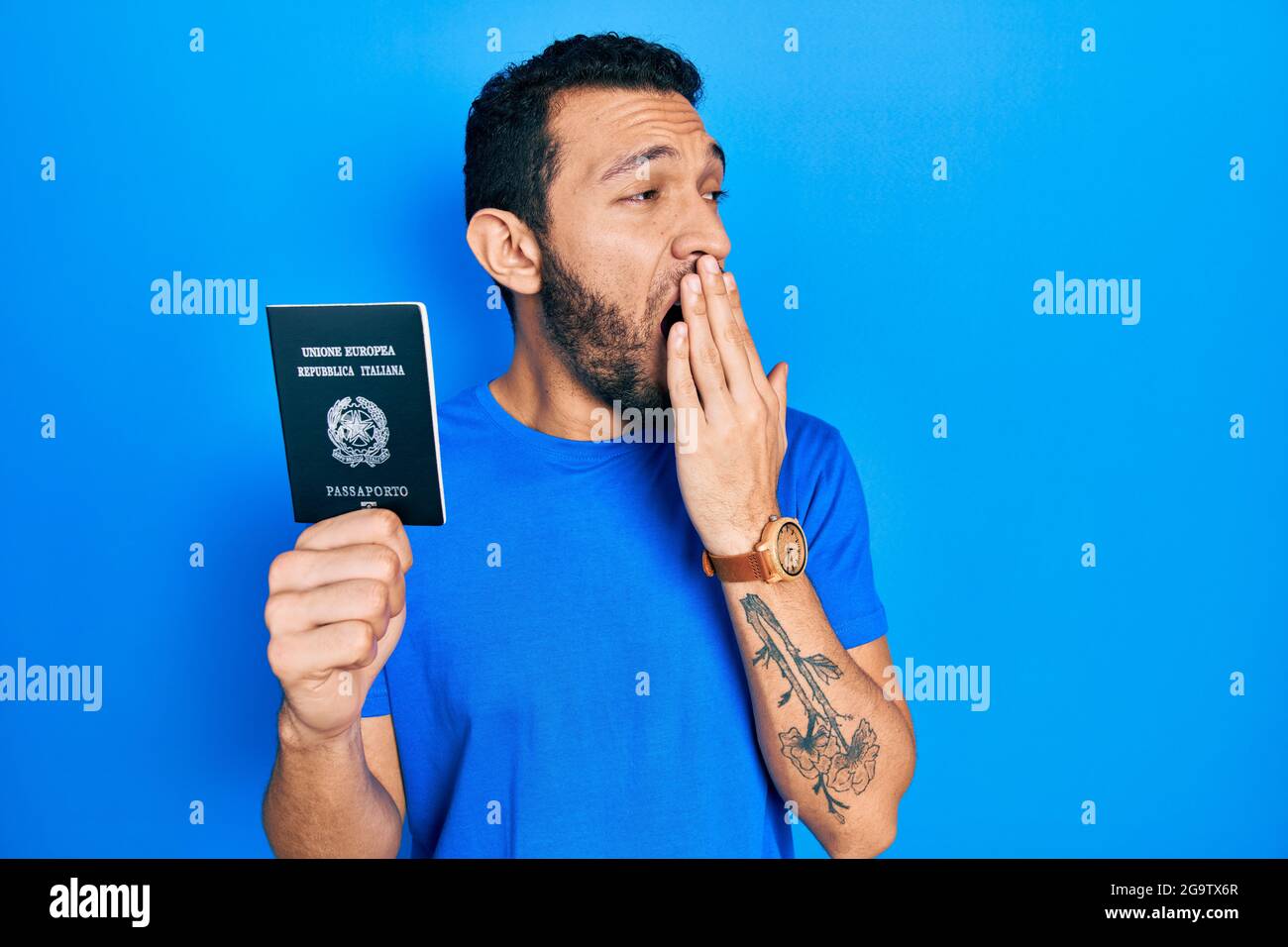Hispanic man with beard holding italy passport bored yawning tired ...
