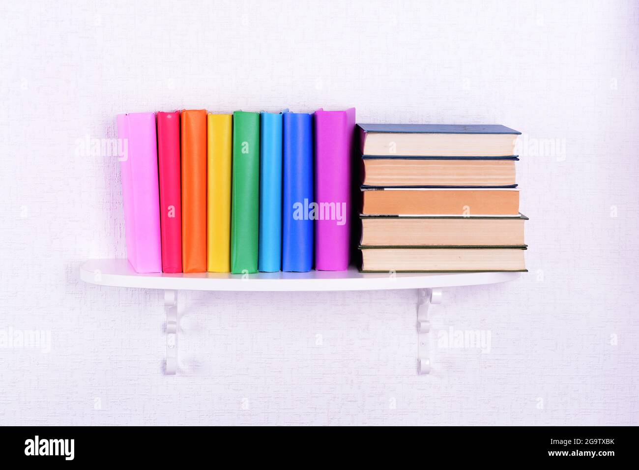Colorful books on shelf on white wall background Stock Photo - Alamy