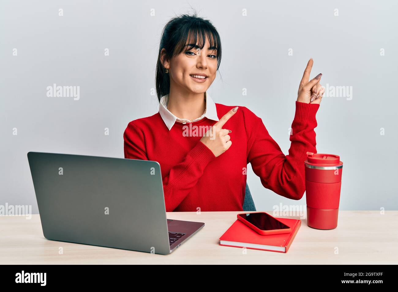 Young brunette woman with bangs working at the office with laptop ...