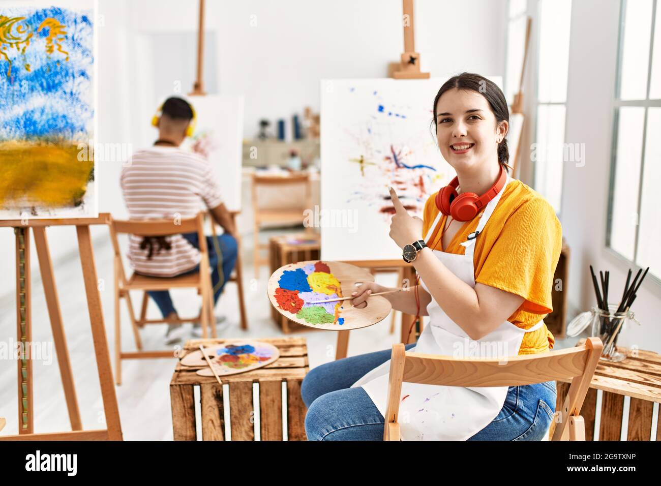 Young artist woman painting on canvas at art studio cheerful with a ...