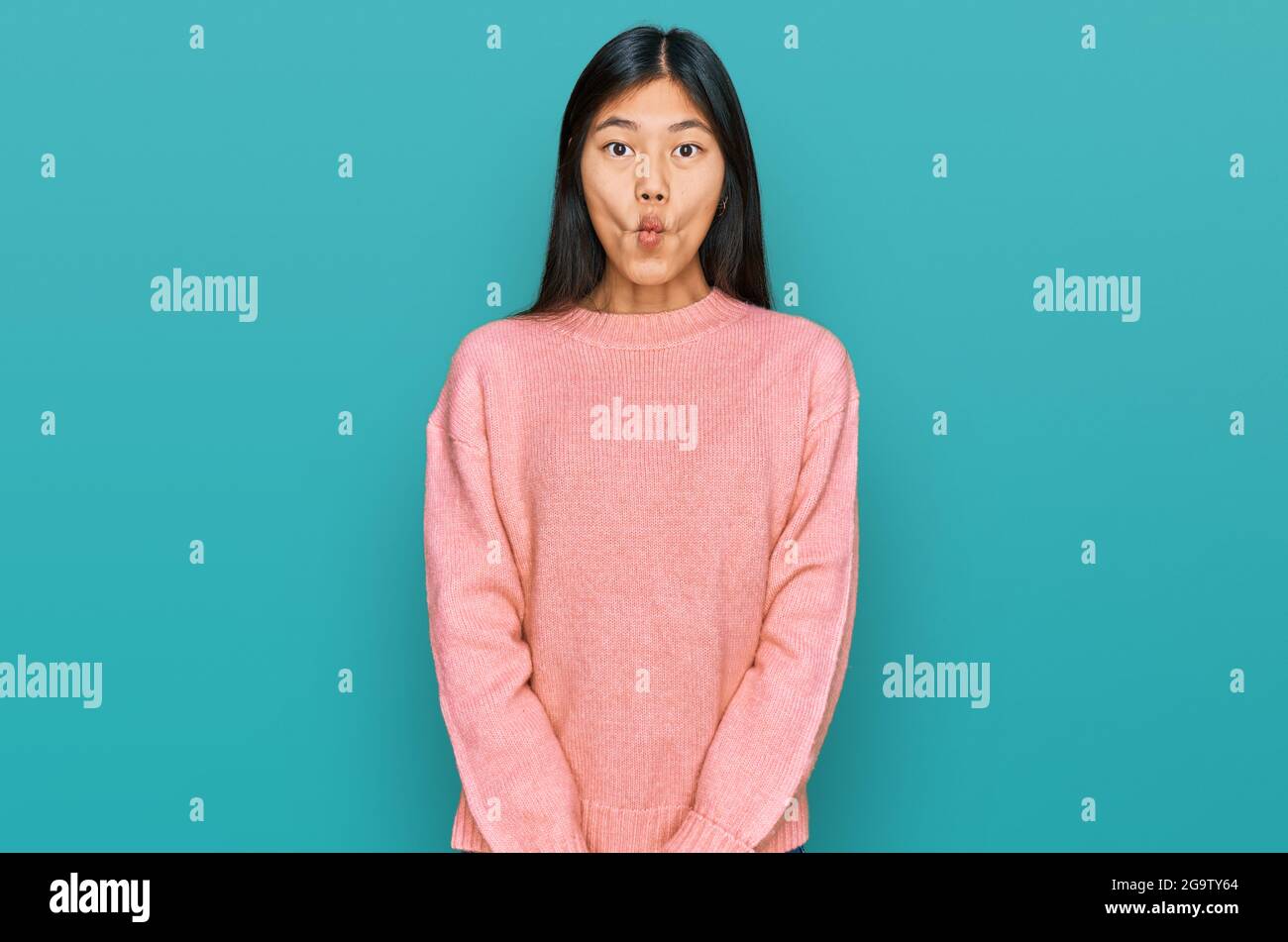 Beautiful young asian woman wearing casual winter sweater making fish ...