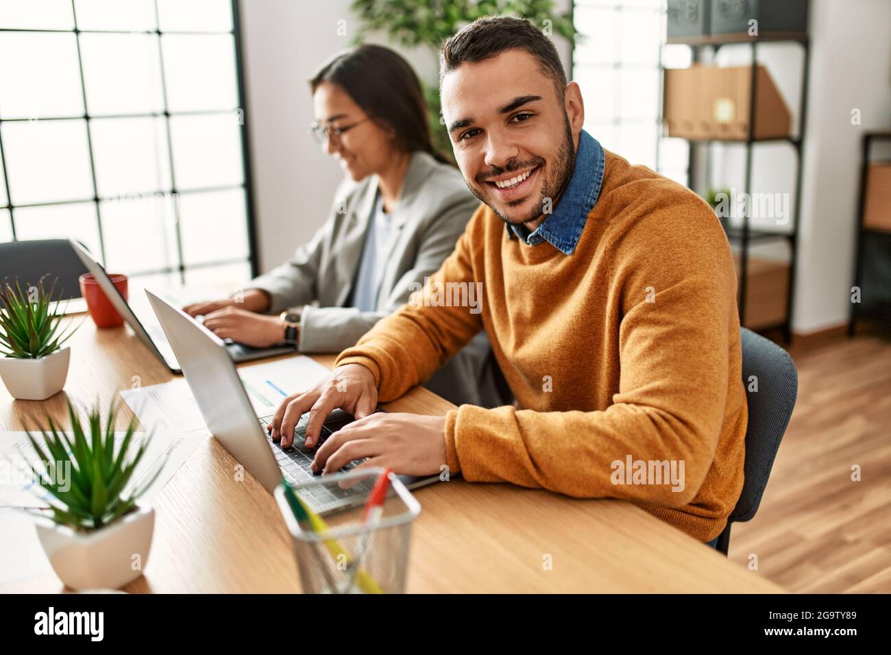 Two business workers smiling happy working sitting on desk at the ...