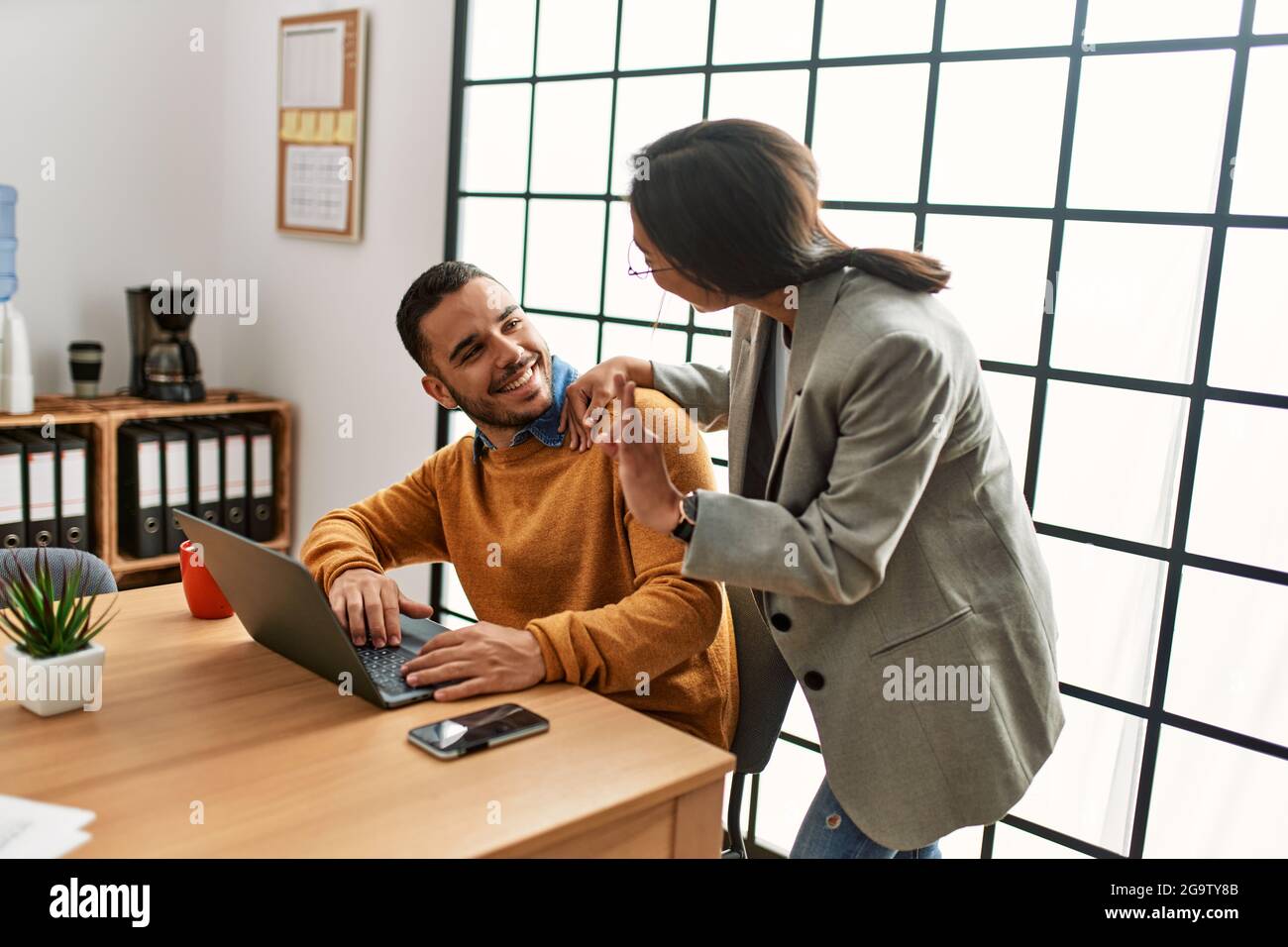 Two business workers smiling happy working sitting on desk at the ...