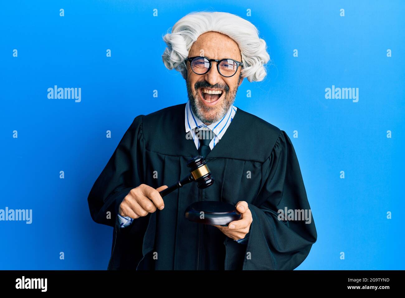 Middle age hispanic man using gavel smiling and laughing hard out loud ...