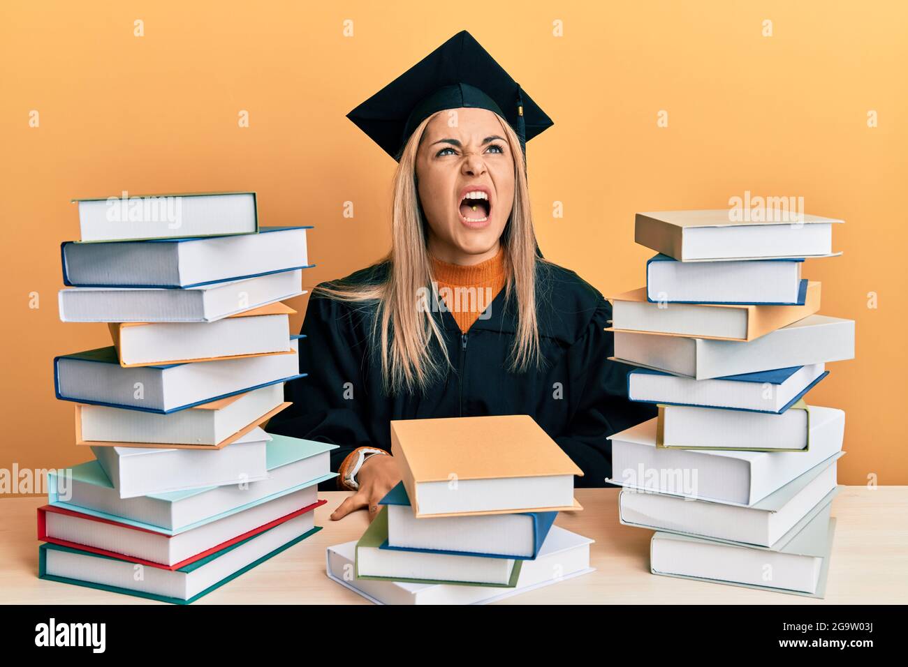 Young caucasian woman wearing graduation ceremony robe sitting on the ...