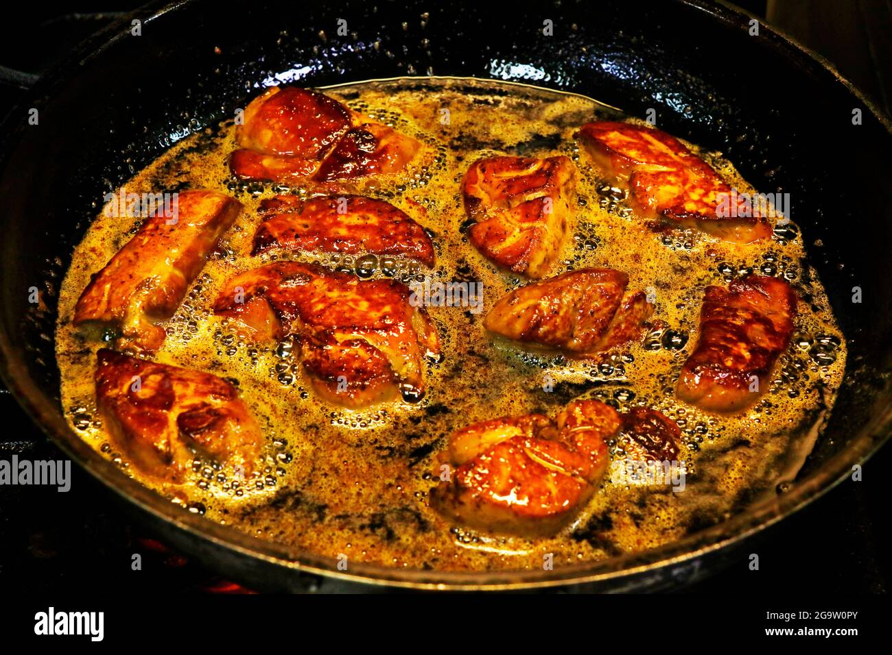 duck or goose liver known as foie gras cooking in a hot pan, oily and ...