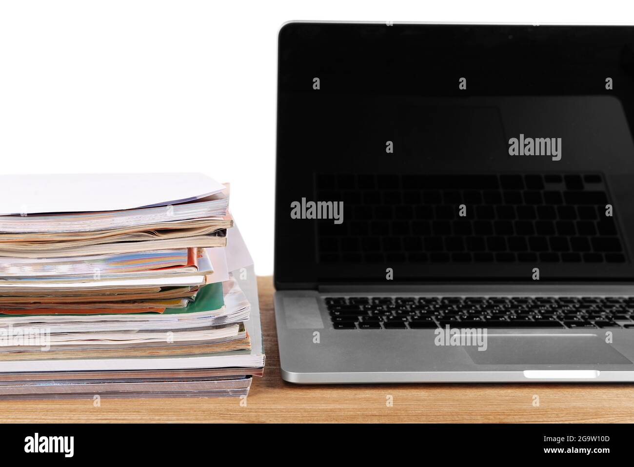 Laptop and stack of magazines on table on white background Stock Photo ...
