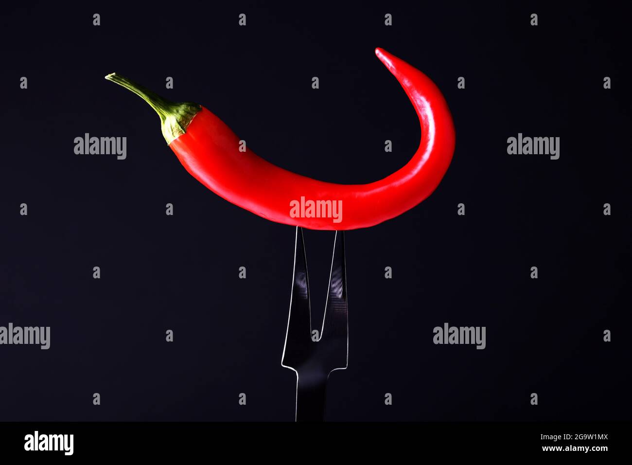 Paper chili on fork on black background Stock Photo - Alamy
