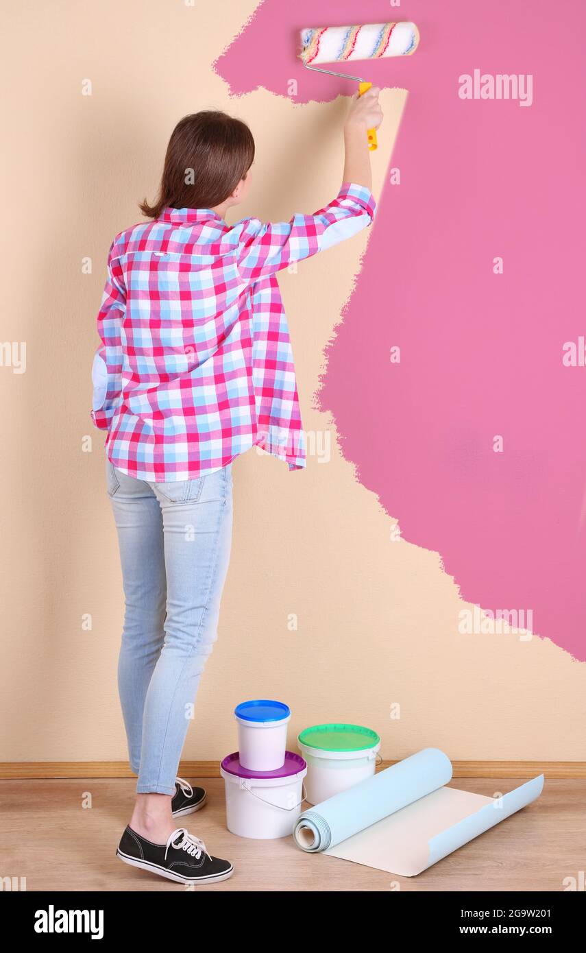 Beautiful woman paints wall in room Stock Photo - Alamy