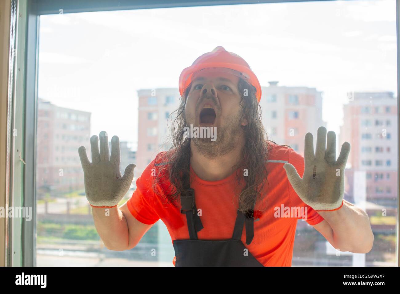 the long-haired engineer in the helmet makes a face behind the glass ...