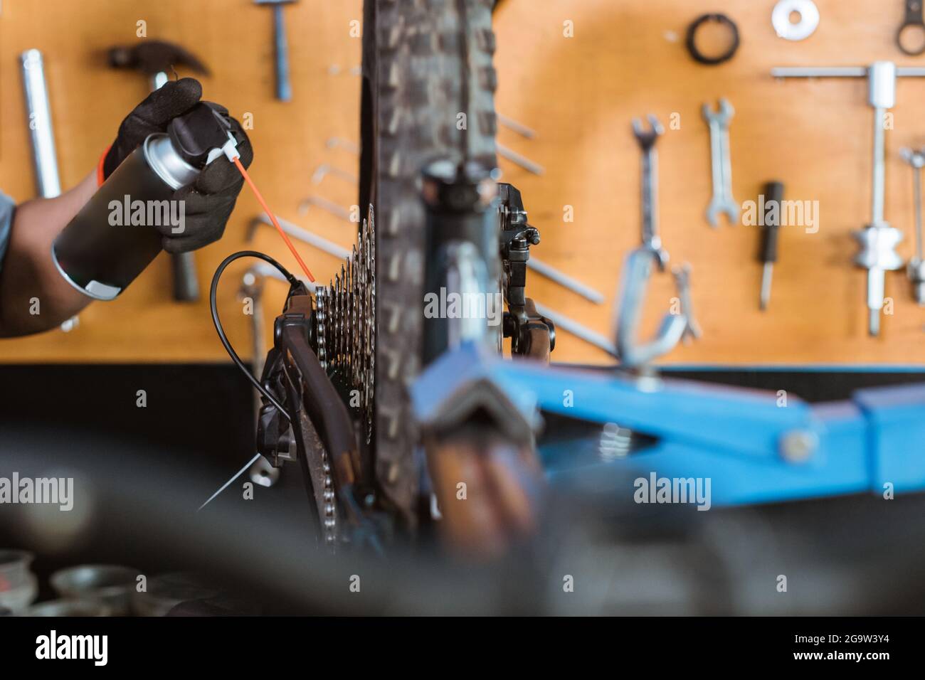 close up of a mechanic's hand wearing gloves using chain lube ...