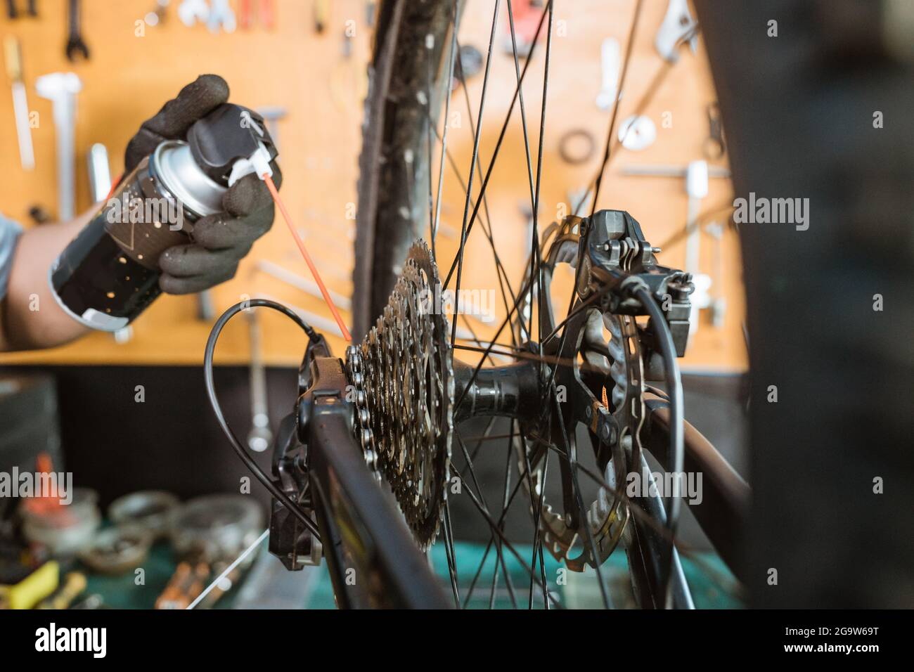 close up of a mechanic's hands wearing gloves using chain lube ...