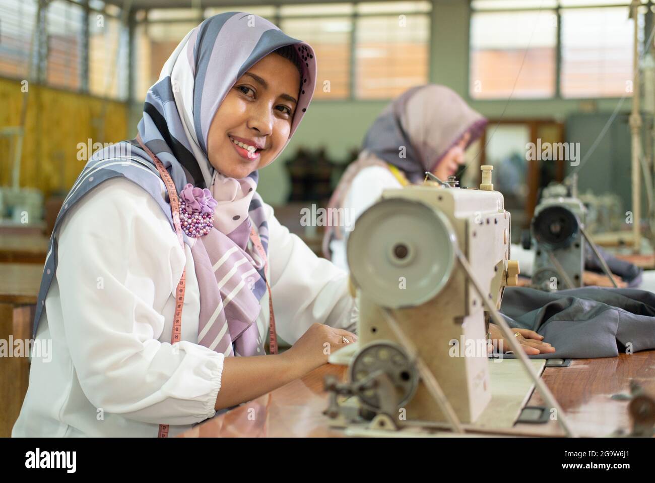 Muslim female employees wearing headscarves smile while working using ...