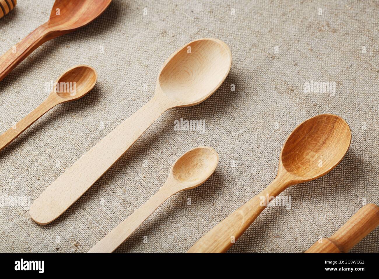 Craft spoons made from different types of wood lie in a row on a hemp ...