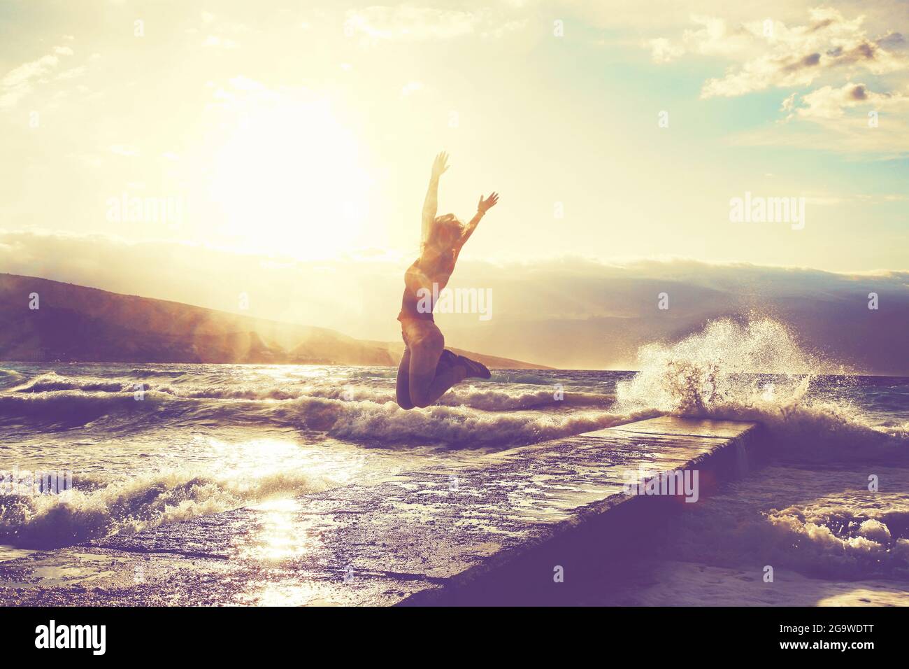 Feeling of freedom concept. Woman jump on pier facing to the sea with ...