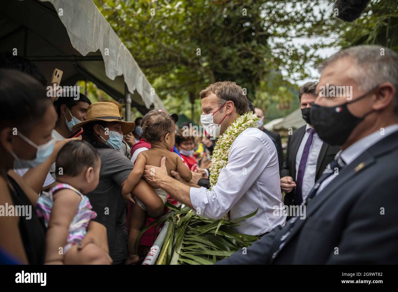 French President Emmanuel Macron (R) holds a baby as he greets local ...