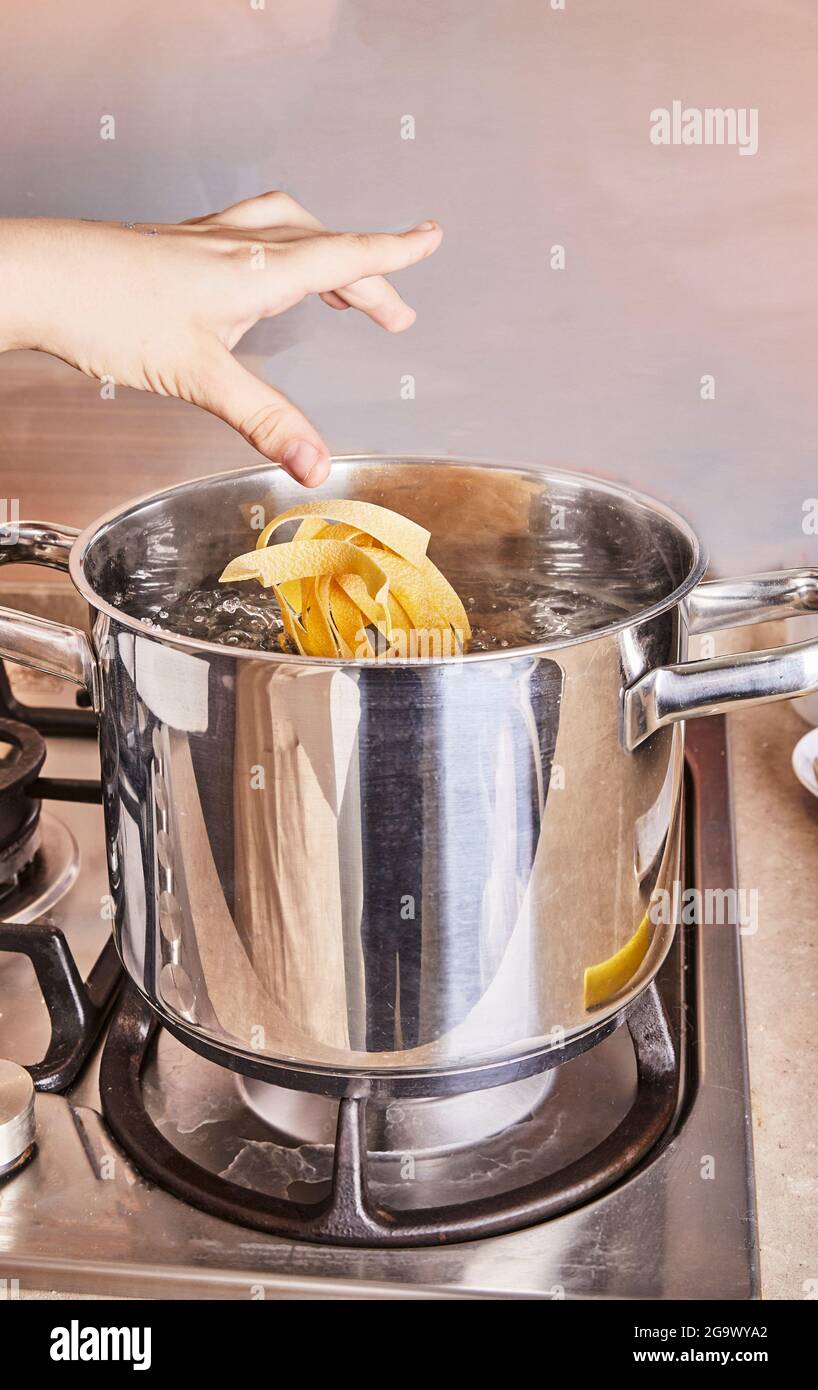 Teenager cooks pasta for making spaghetti bolognese according to recipe ...