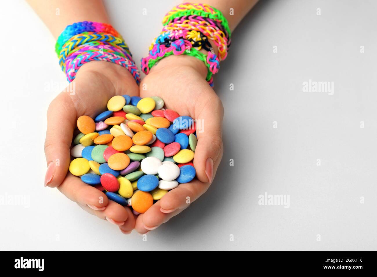 Female hands with bracelets and pile of colorful candies isolated on ...