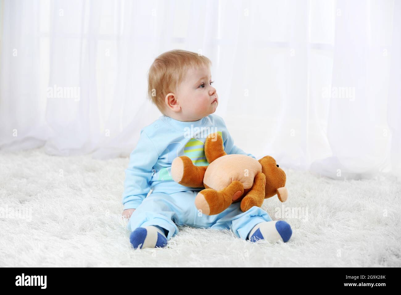 Cute baby boy with teddy bear on carpet, on light background Stock ...