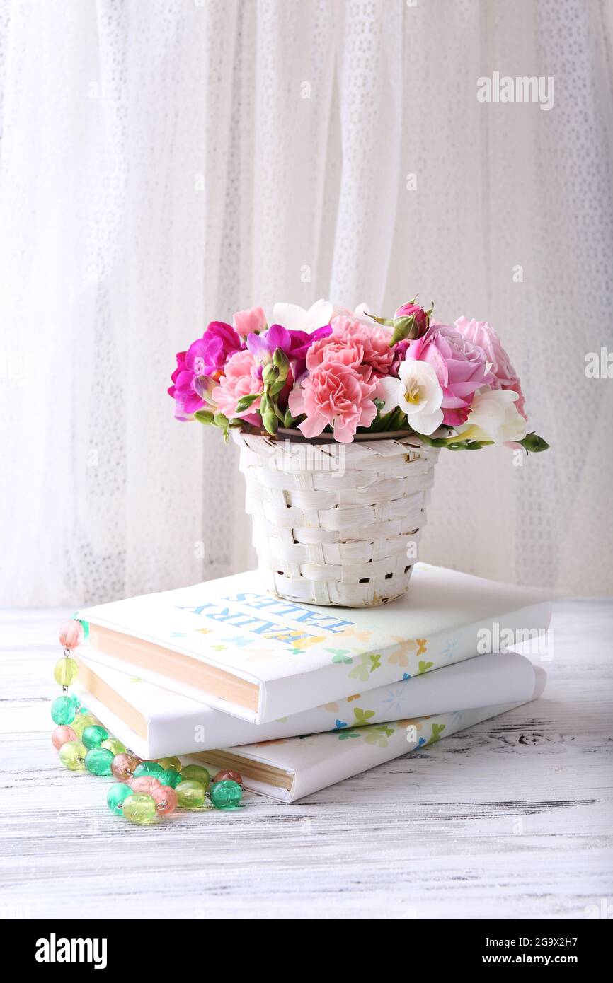 Beautiful fresh spring flowers with stack of books on curtain ...