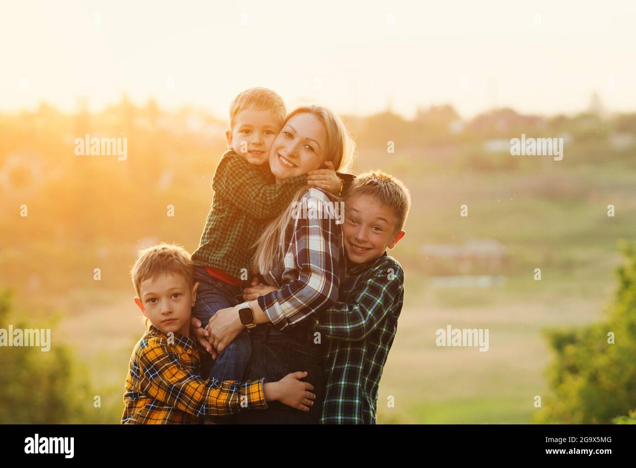 Happy mother and her three son are playing at sunset time. Friendly ...