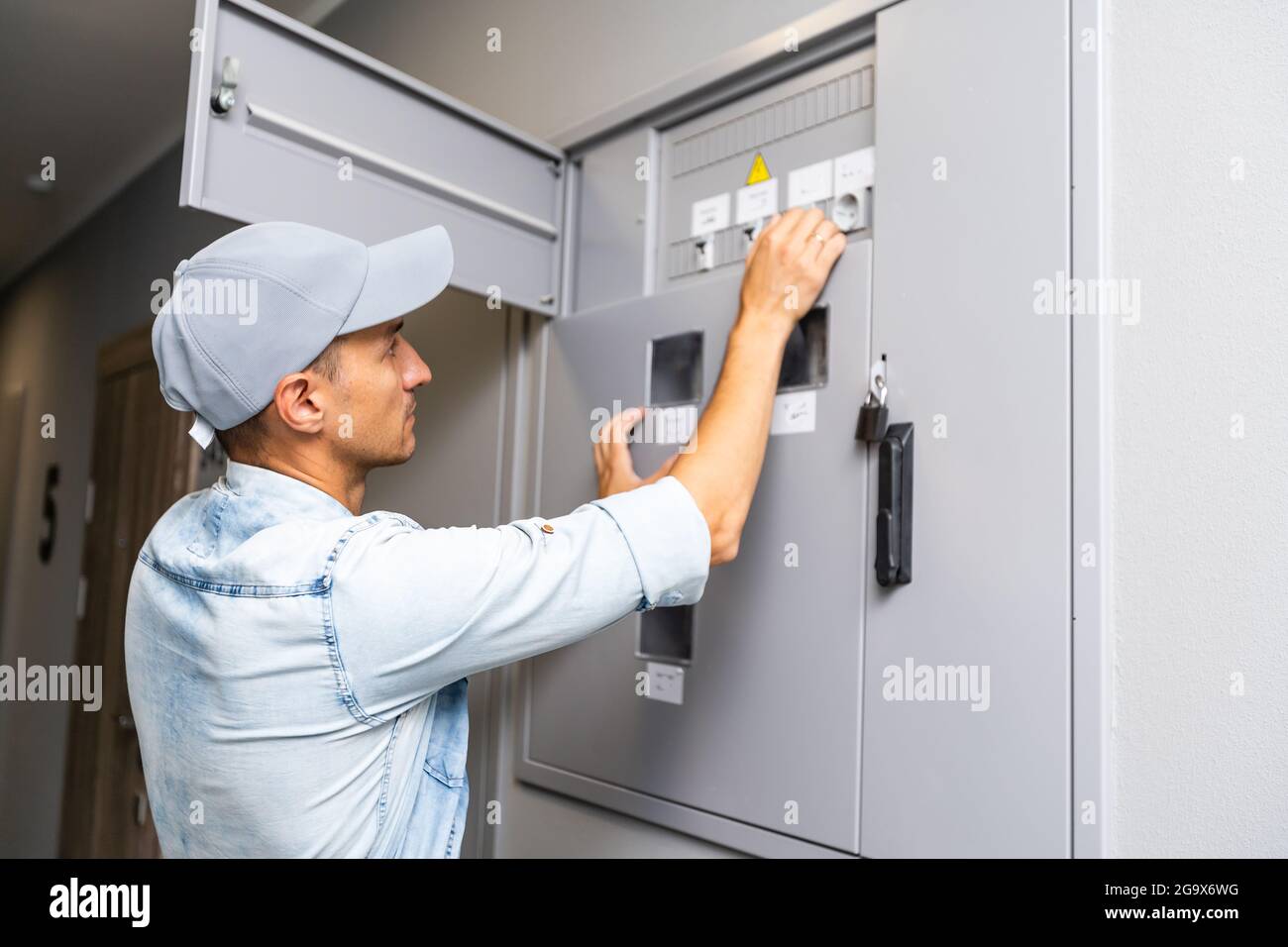 Young smiling electrician doing his work, electrical panel Stock Photo ...