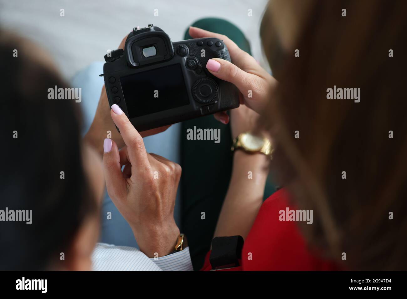 Two women hold camera in their hands and press buttons Stock Photo - Alamy