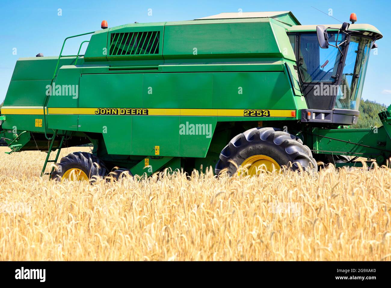 John Deere combine harvester in ripe rye field on a beautiful day of ...