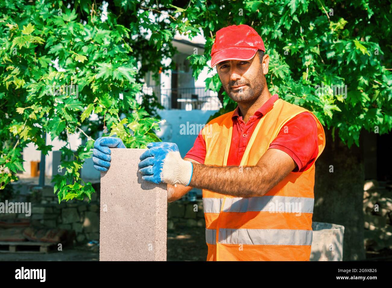 Turkish pavement construction worker holds a big tile of pavement stone ...