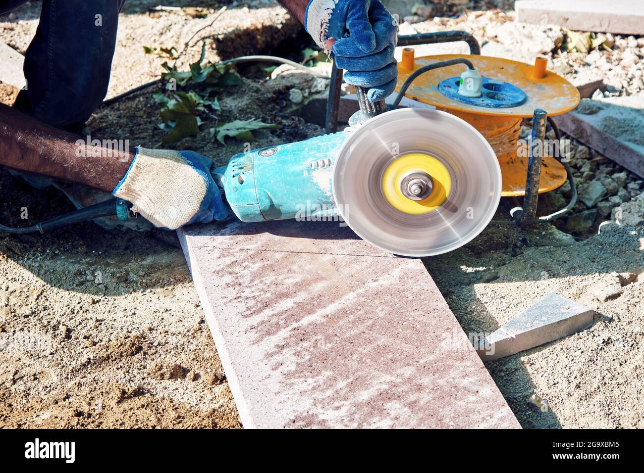 Hands of a pavement construction worker using an angle grinder for ...