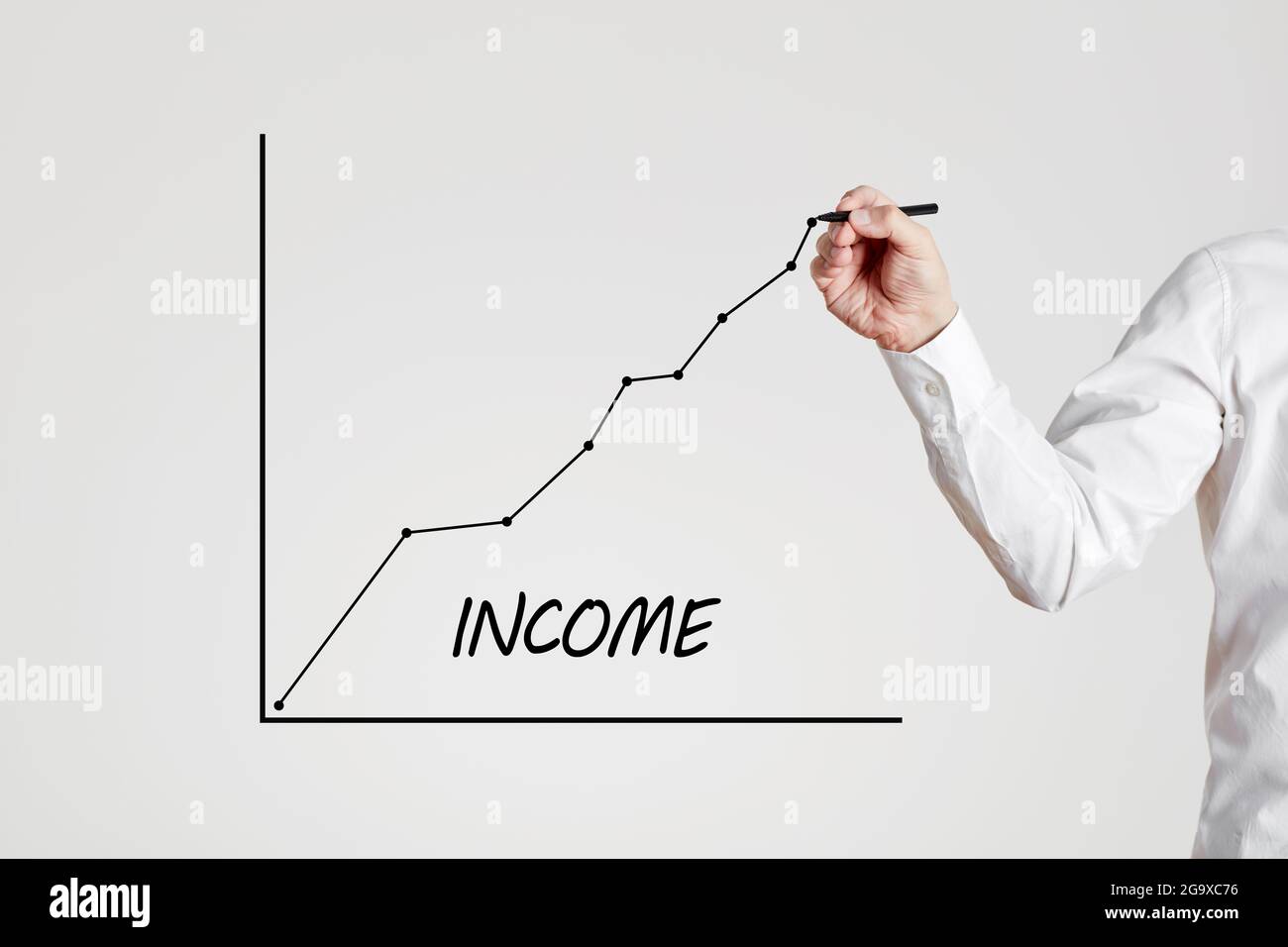 Businessman hand draws a rising line graph with the word income on gray ...