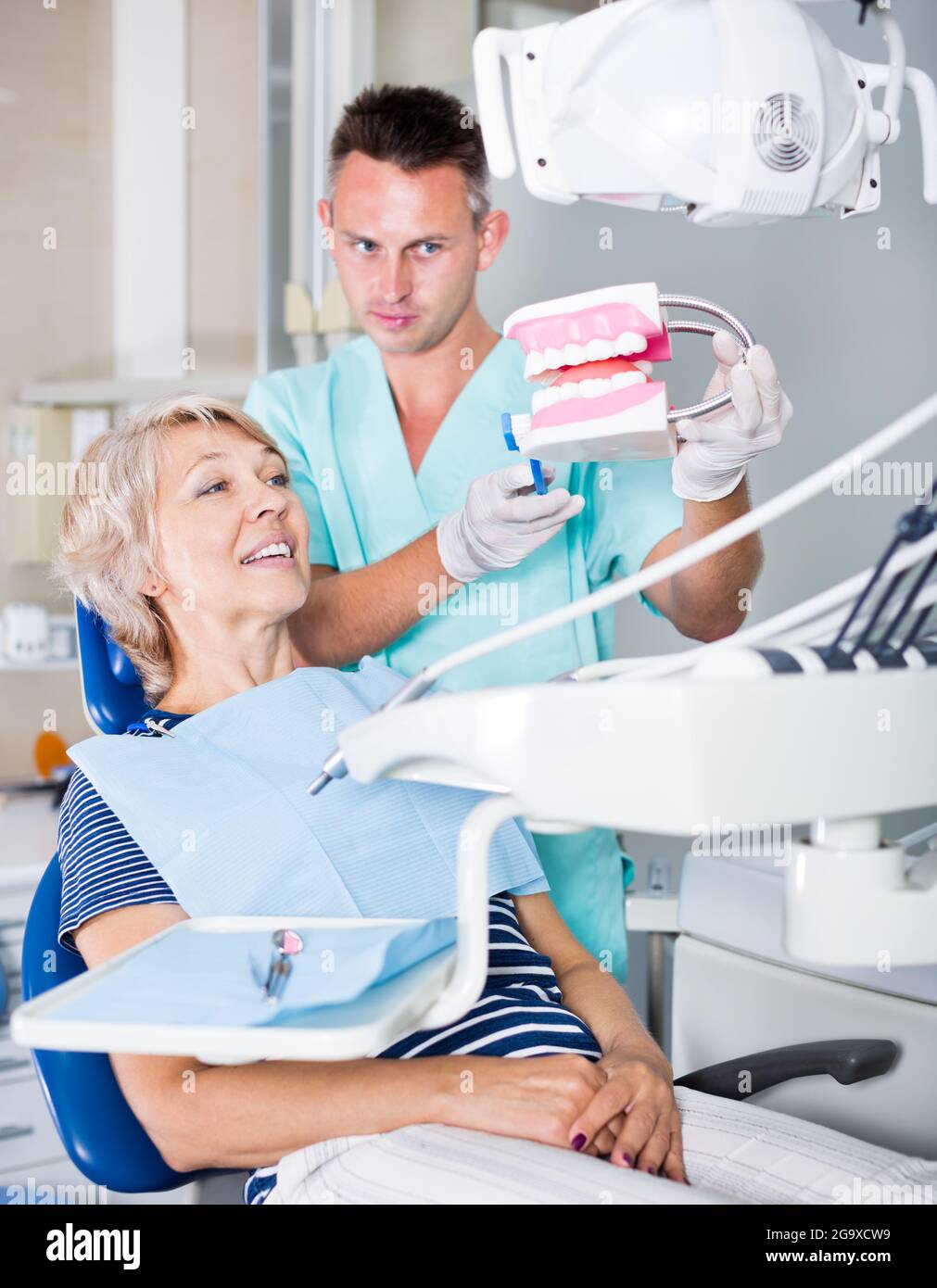 Dentist explaining to patient correct tooth brushing Stock Photo - Alamy