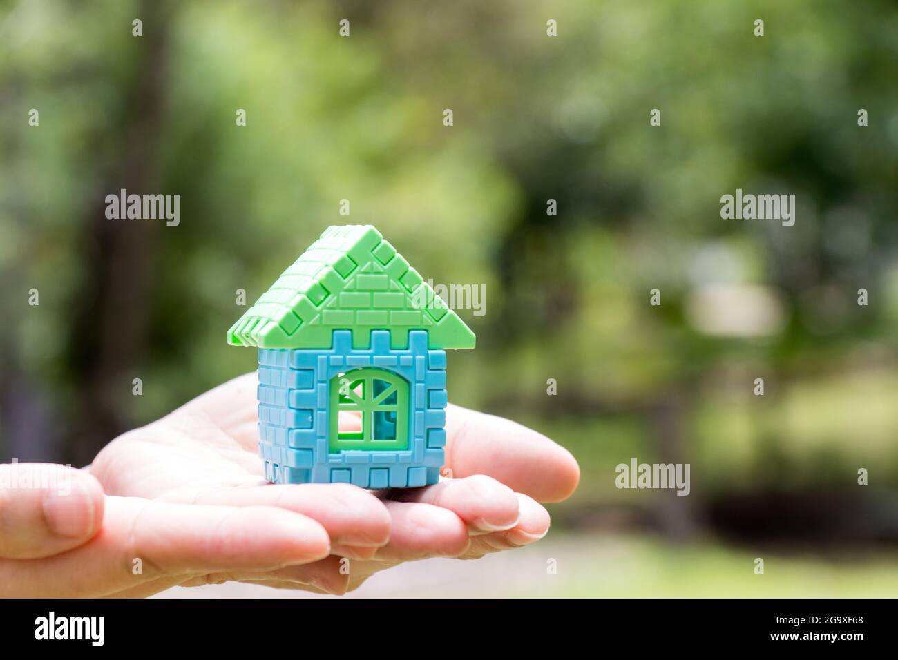 Woman hand hold home block model with blur green background (Concept ...