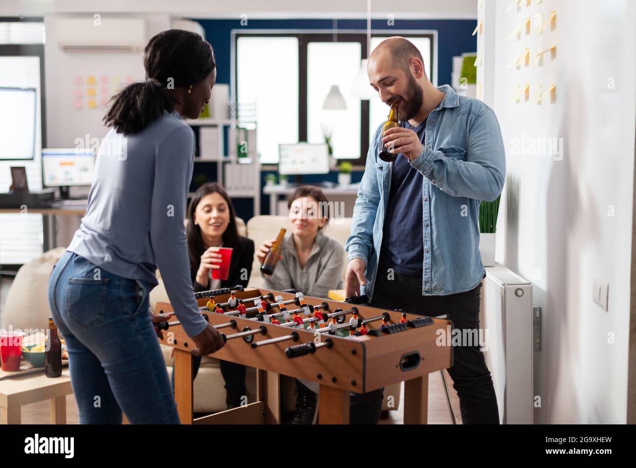 Diverse workers celebrate playing foosball, table football soccer after ...
