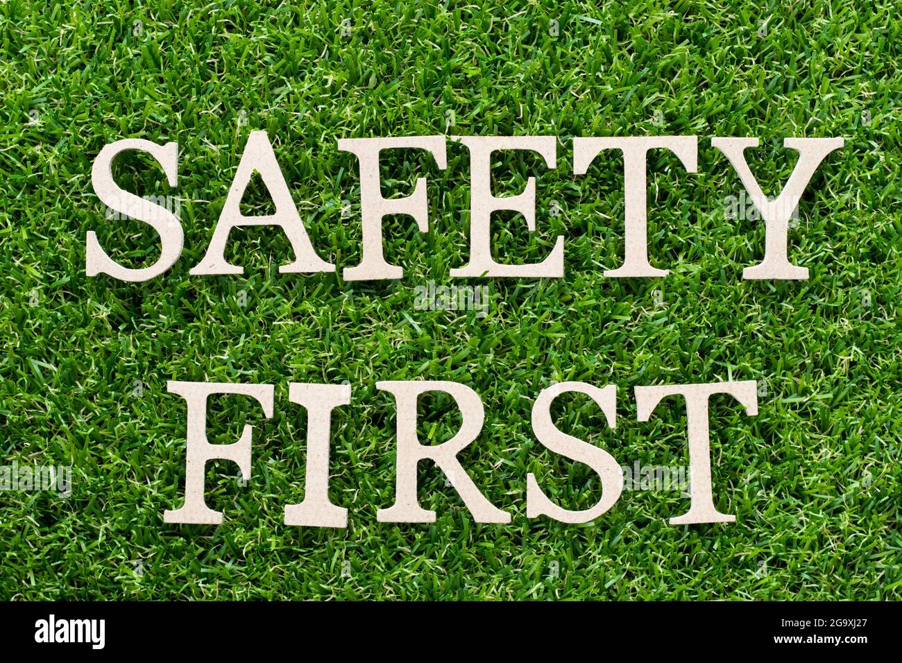 Wood alphabet in word safety first on artificial green grass background ...