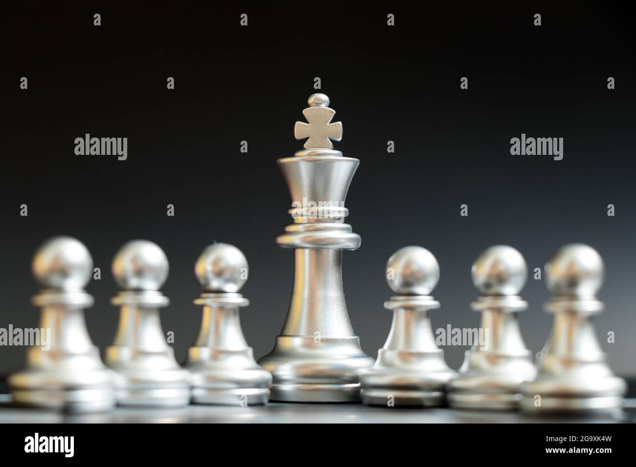 Silver king chess piece stand with pawn on black background Stock Photo ...