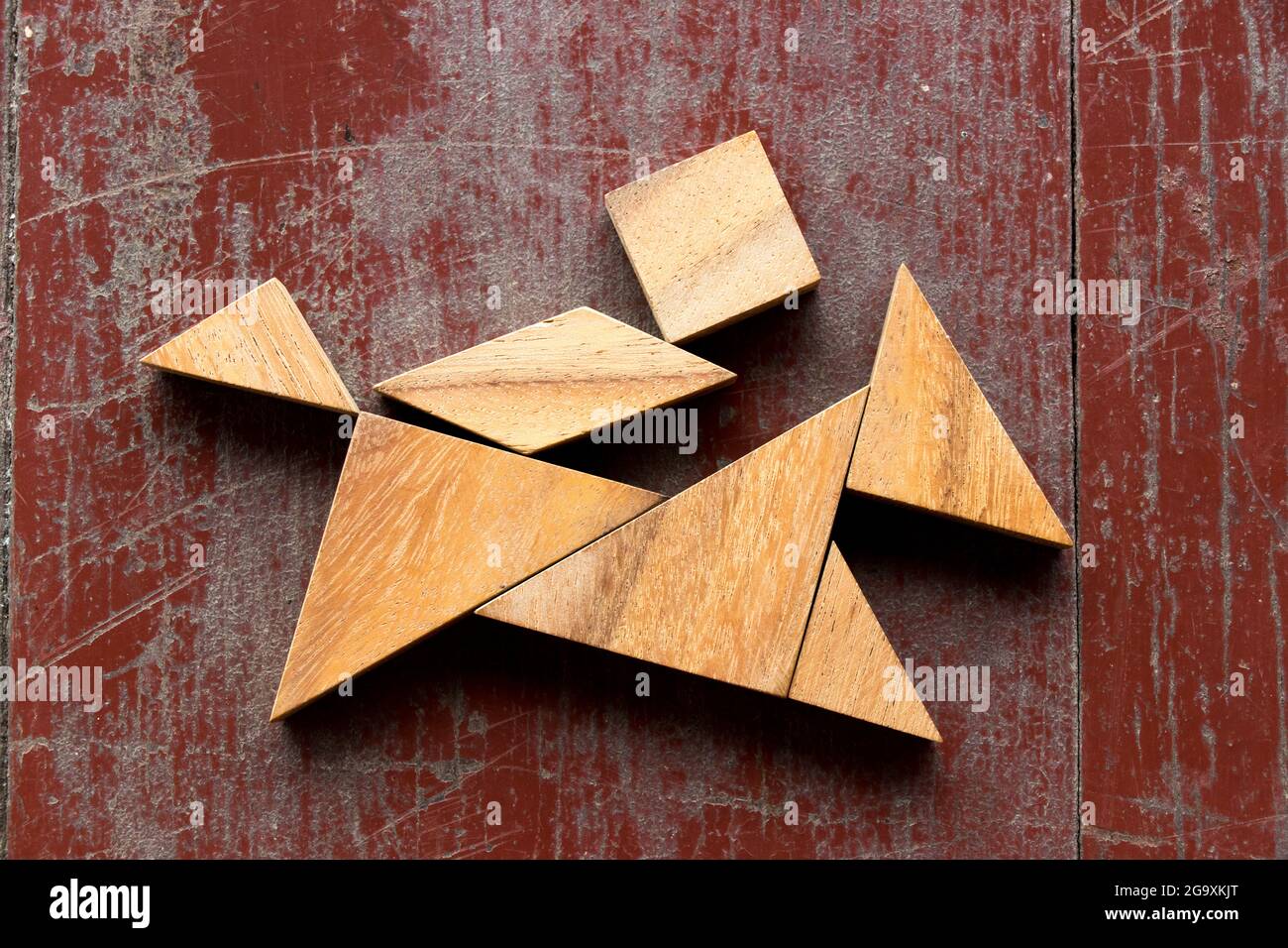 Tangram puzzle in man riding horse shape on red old wood background ...