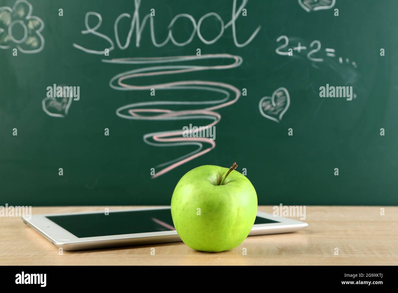 Digital tablet and apple on desk in front of blackboard Stock Photo - Alamy
