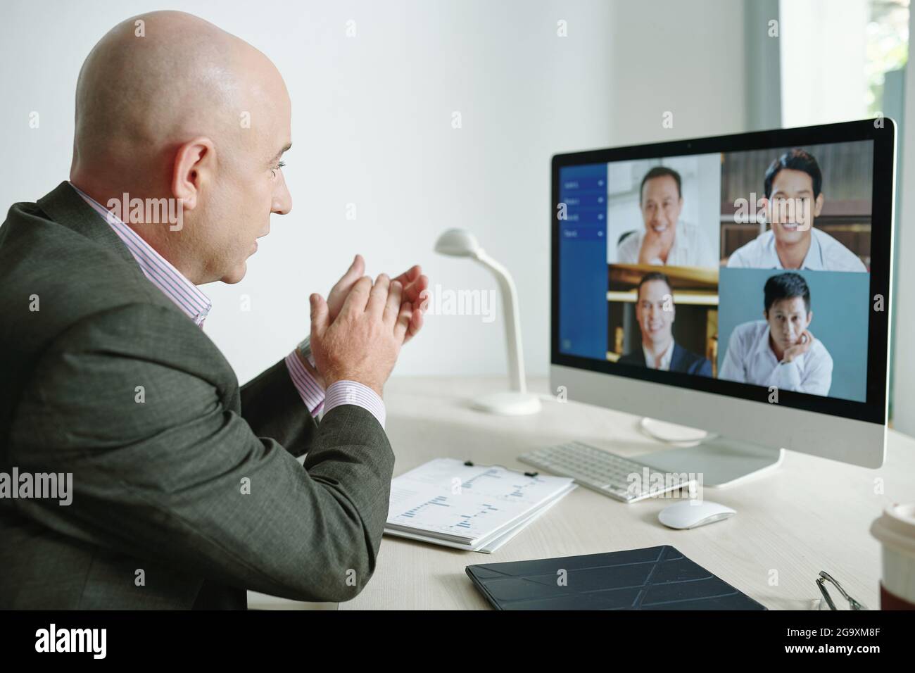 Mature businessman clapping hands while sitting at the table in front ...