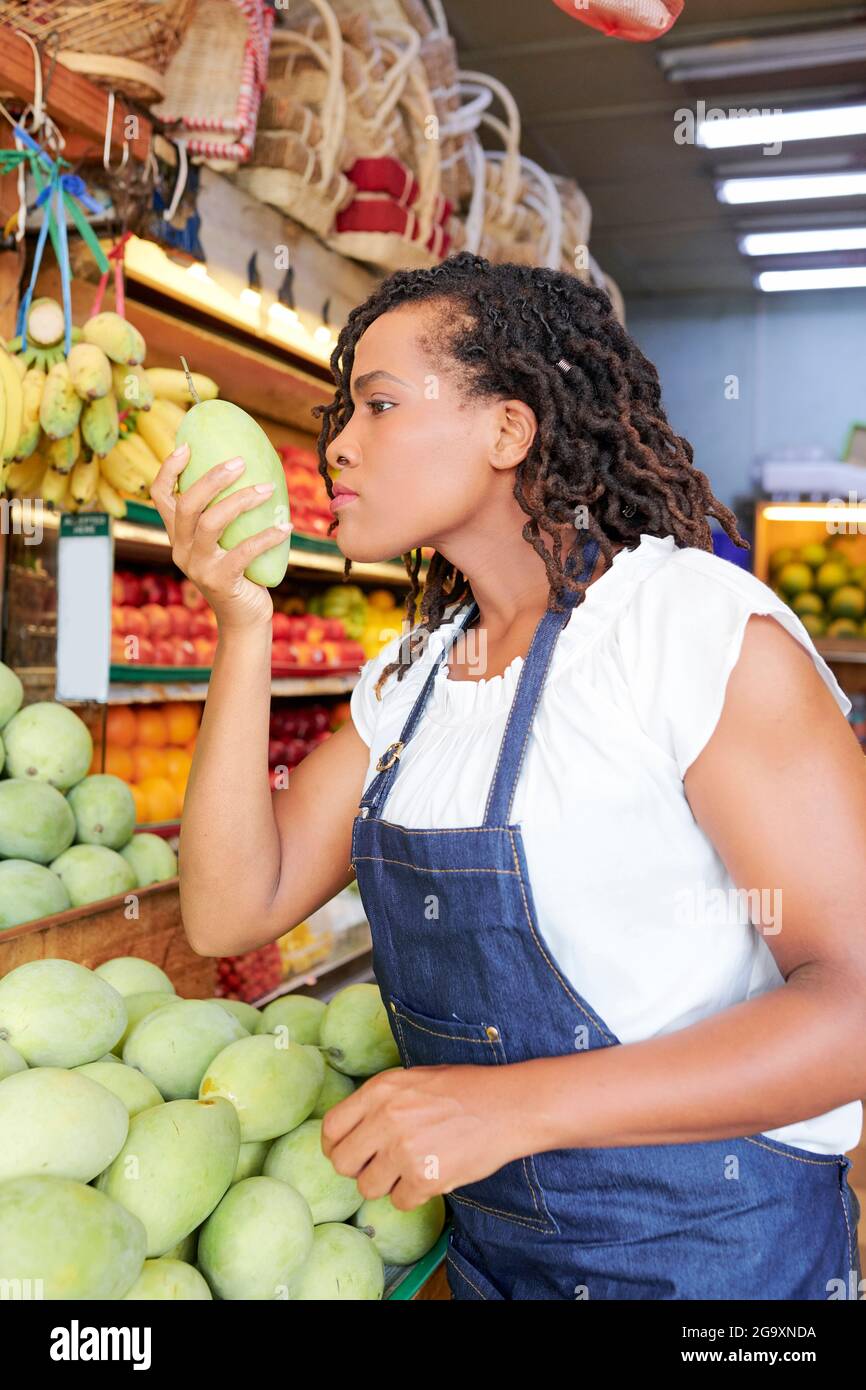 African young woman choosing the fruits in the shop, she smelling the ...