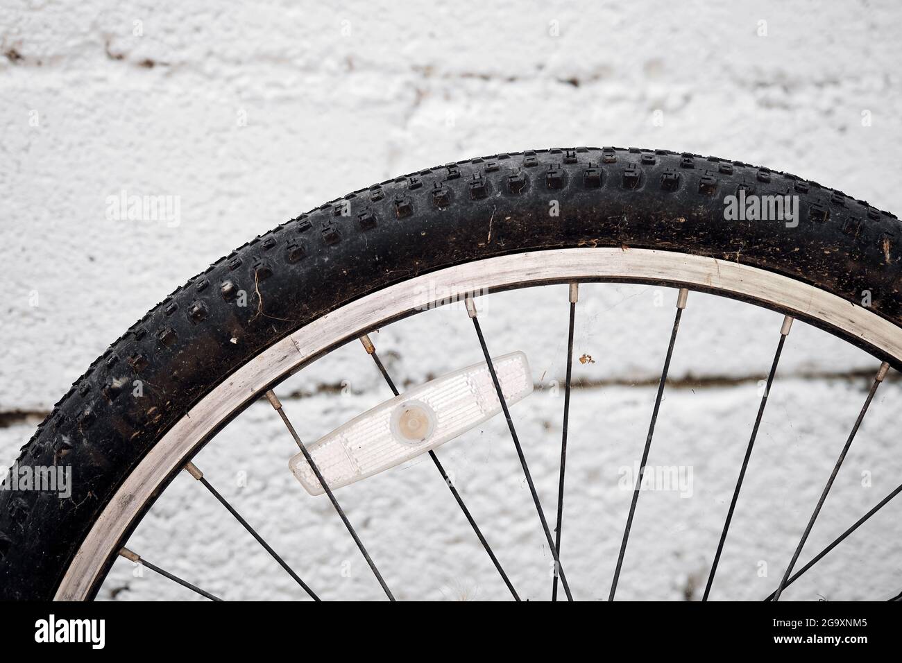 Close up side view detail of a bicycle wheel with white stone wall ...