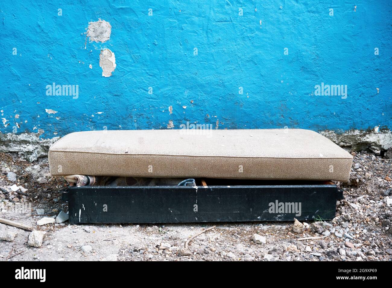 Old dumped junk mattress and bed in front of a blue wall Stock Photo ...