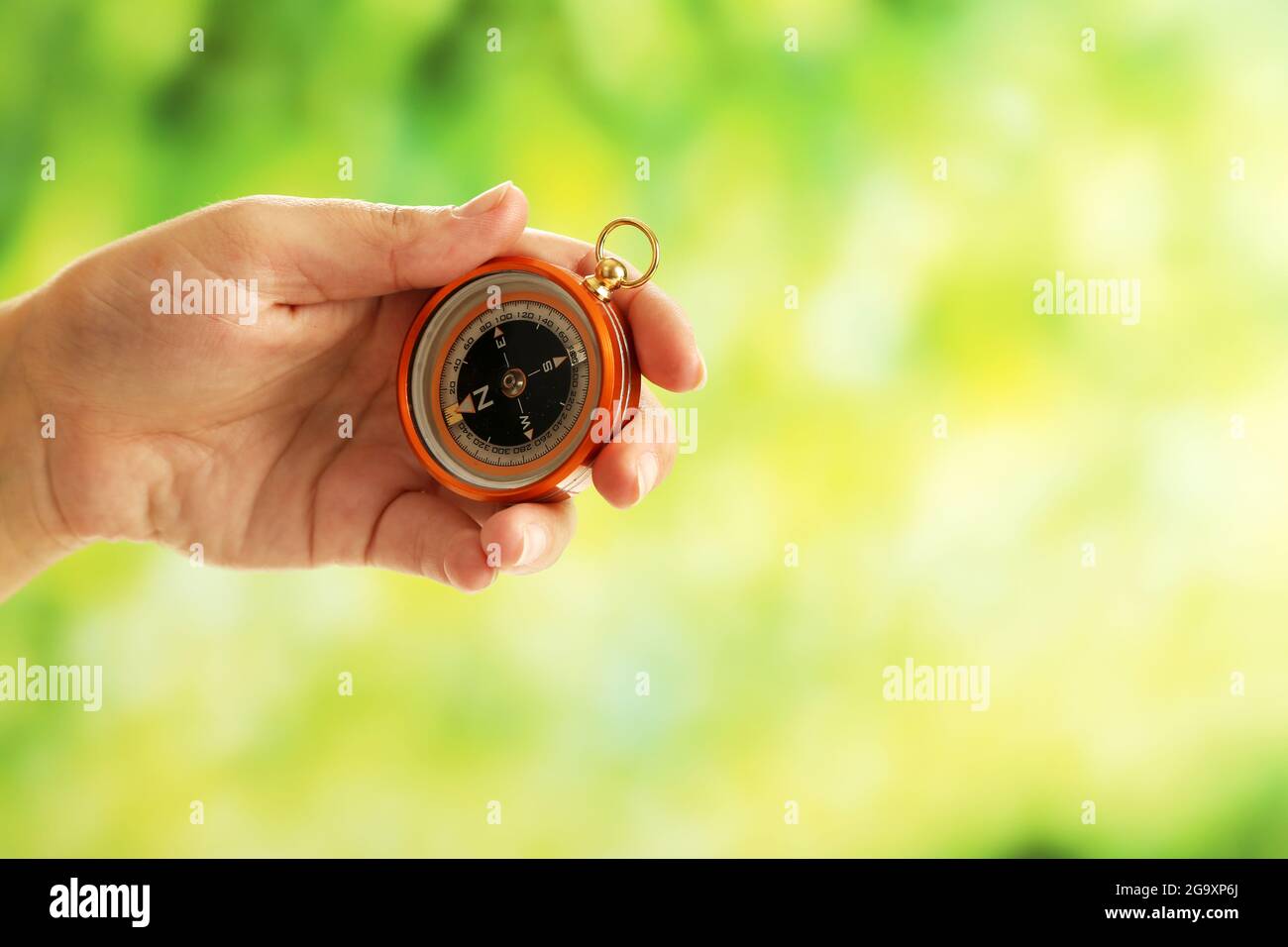 Female hand with compass on bright blurred background Stock Photo - Alamy